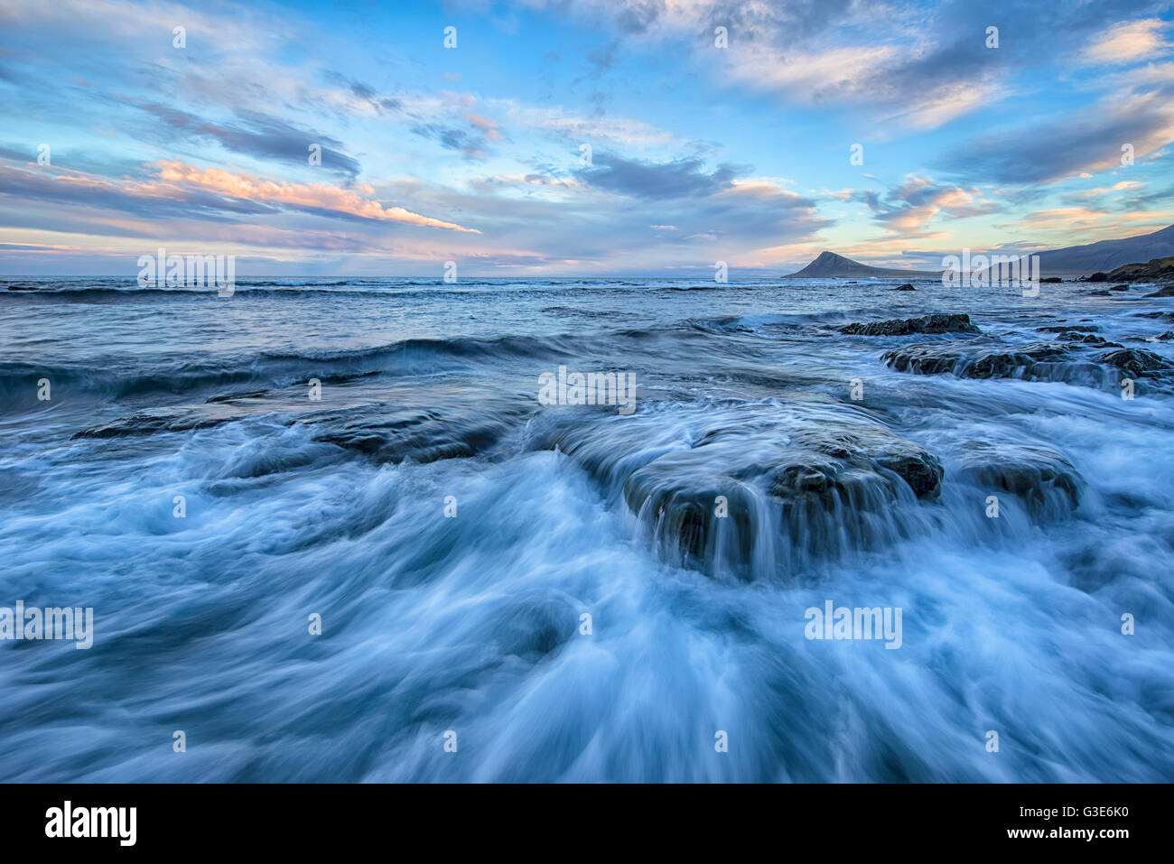 The surf of the Atlantic Ocean crash over rocks; West Fjords, Iceland ...