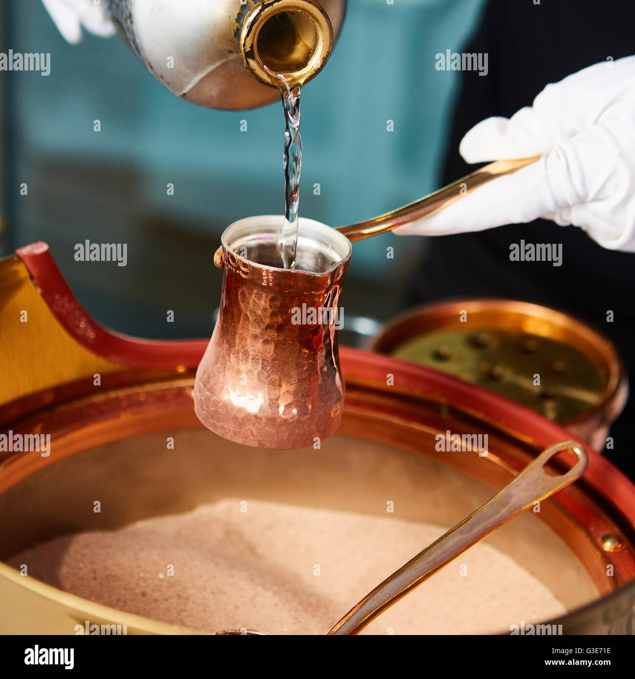 Preparation of Turkish coffee in the cezve in the sand at cafe bar ...