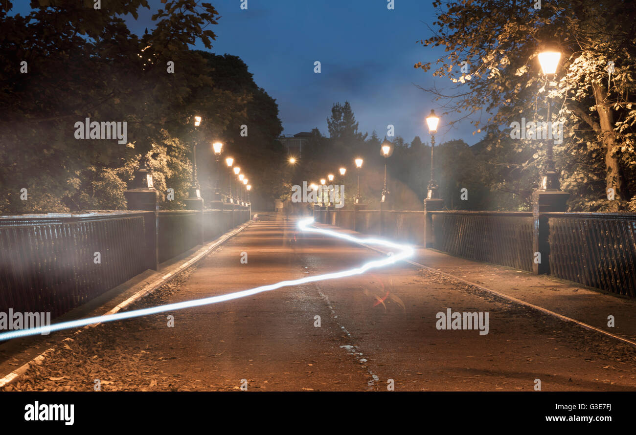 Light trail glowing in a path lit by lamp posts at dusk; Newcastle ...