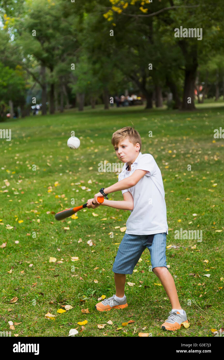 Young boy hitting a baseball in a park; Edmonton, Alberta, Canada Stock ...