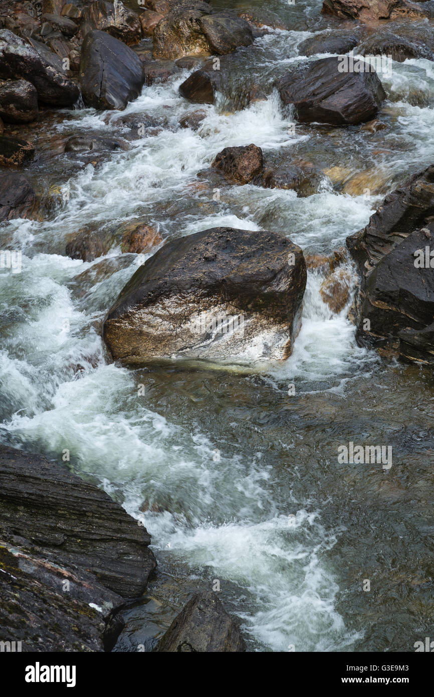 Boulders lie in a Scottish burn in spate, Western Highlands, Scotland ...