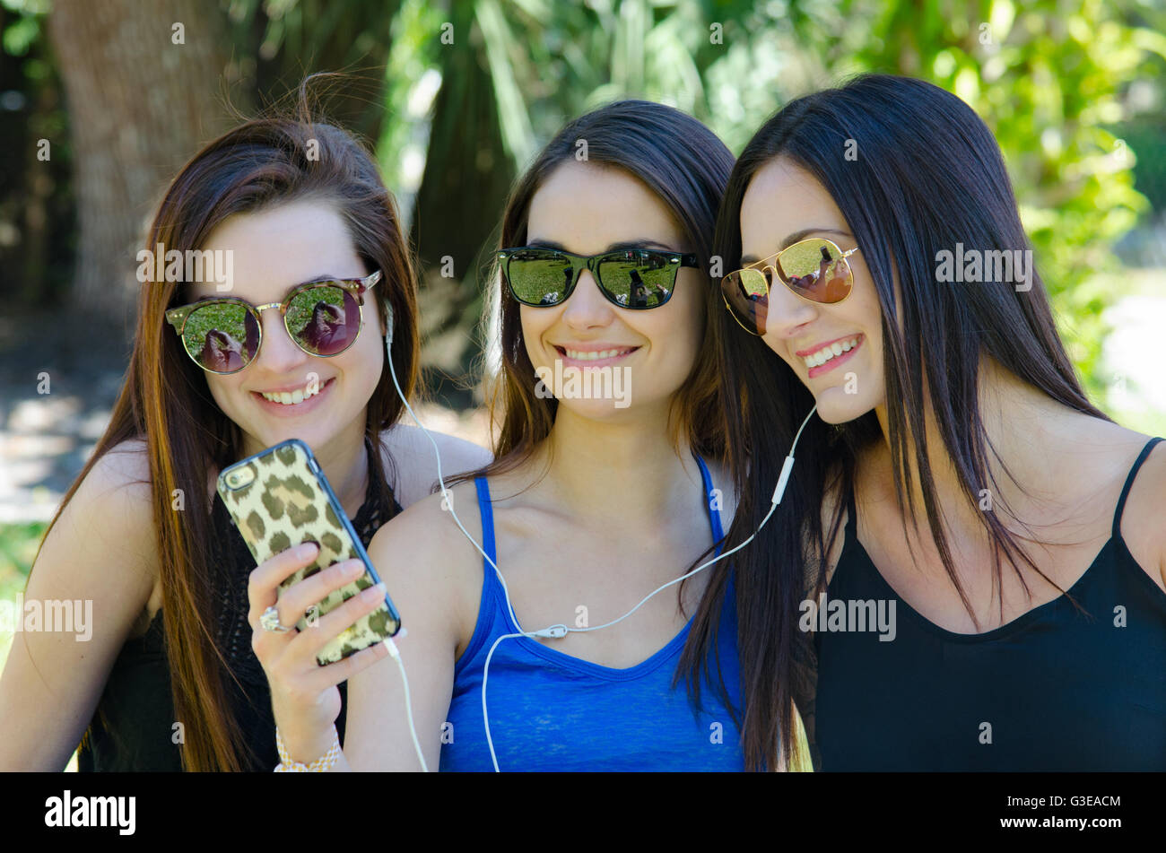 Three young female friends using smartphone listening to music in ...