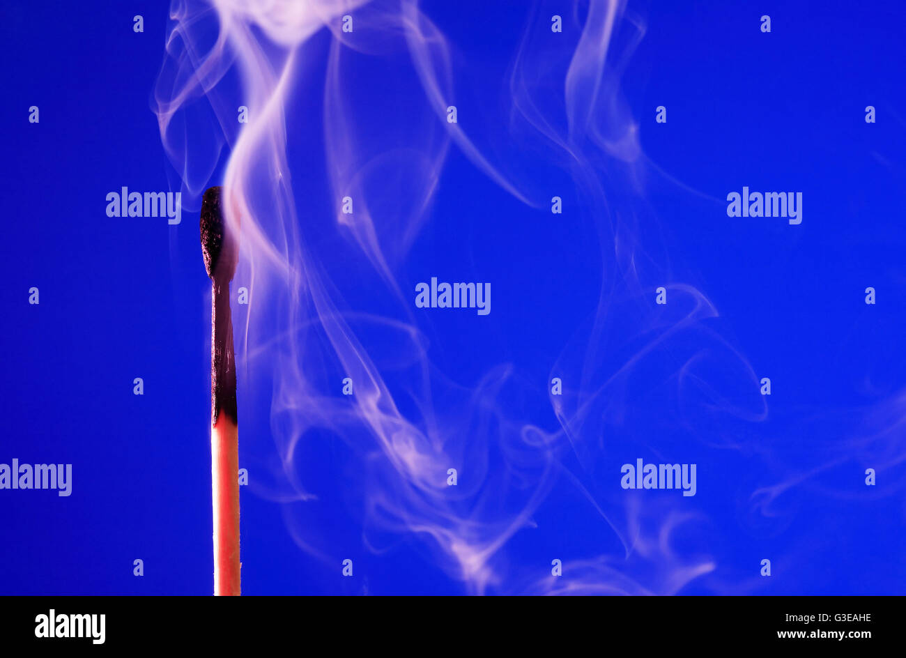 Extinguished match with smoke on blue background Stock Photo - Alamy