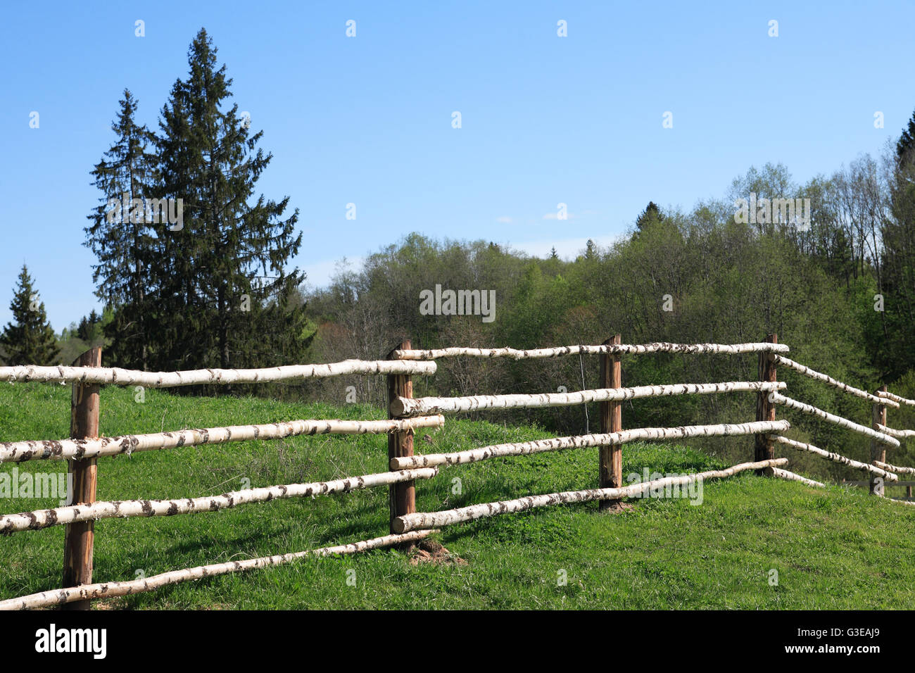 Fence made from wooden poles around field at summer Stock Photo - Alamy