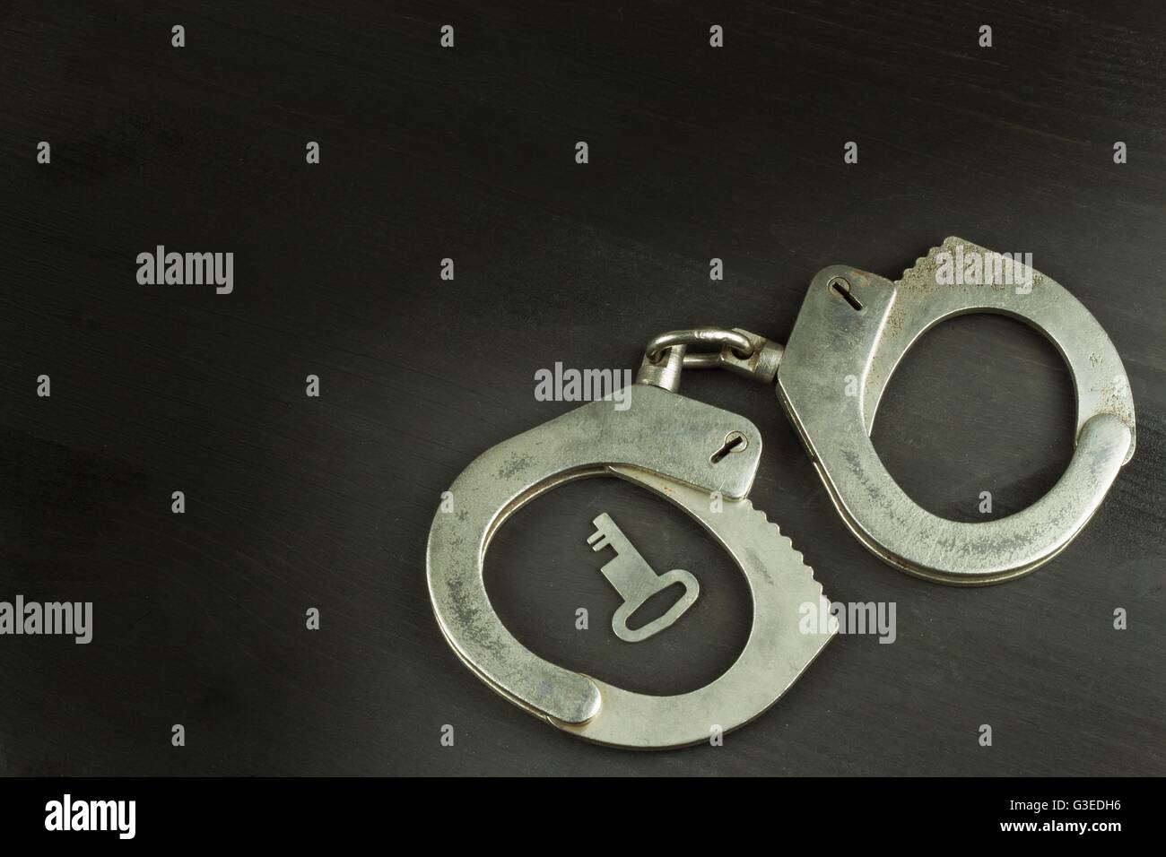 Metal police handcuffs on a dark wooden board. Silver handcuffs ...