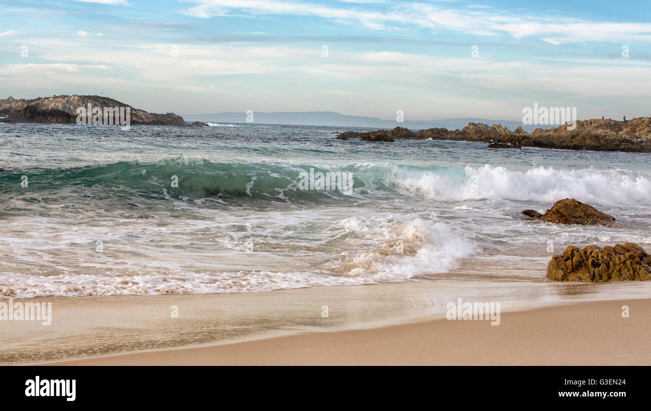 blue ocean waves and sandy beach with rocks and blue sky Stock Photo ...