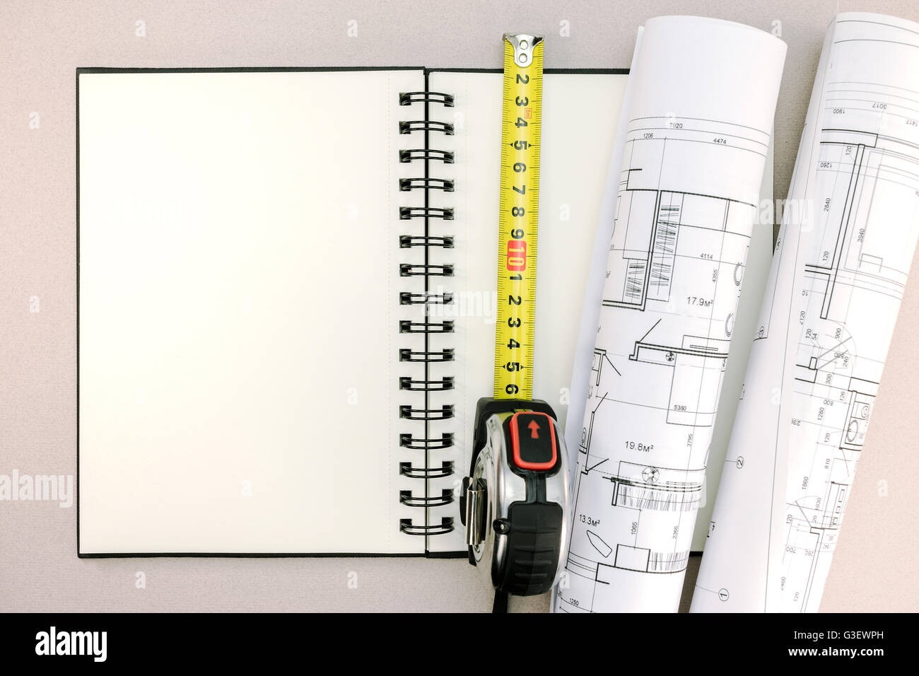 rolls of architectural blueprints with notepad and tape measure on desk ...