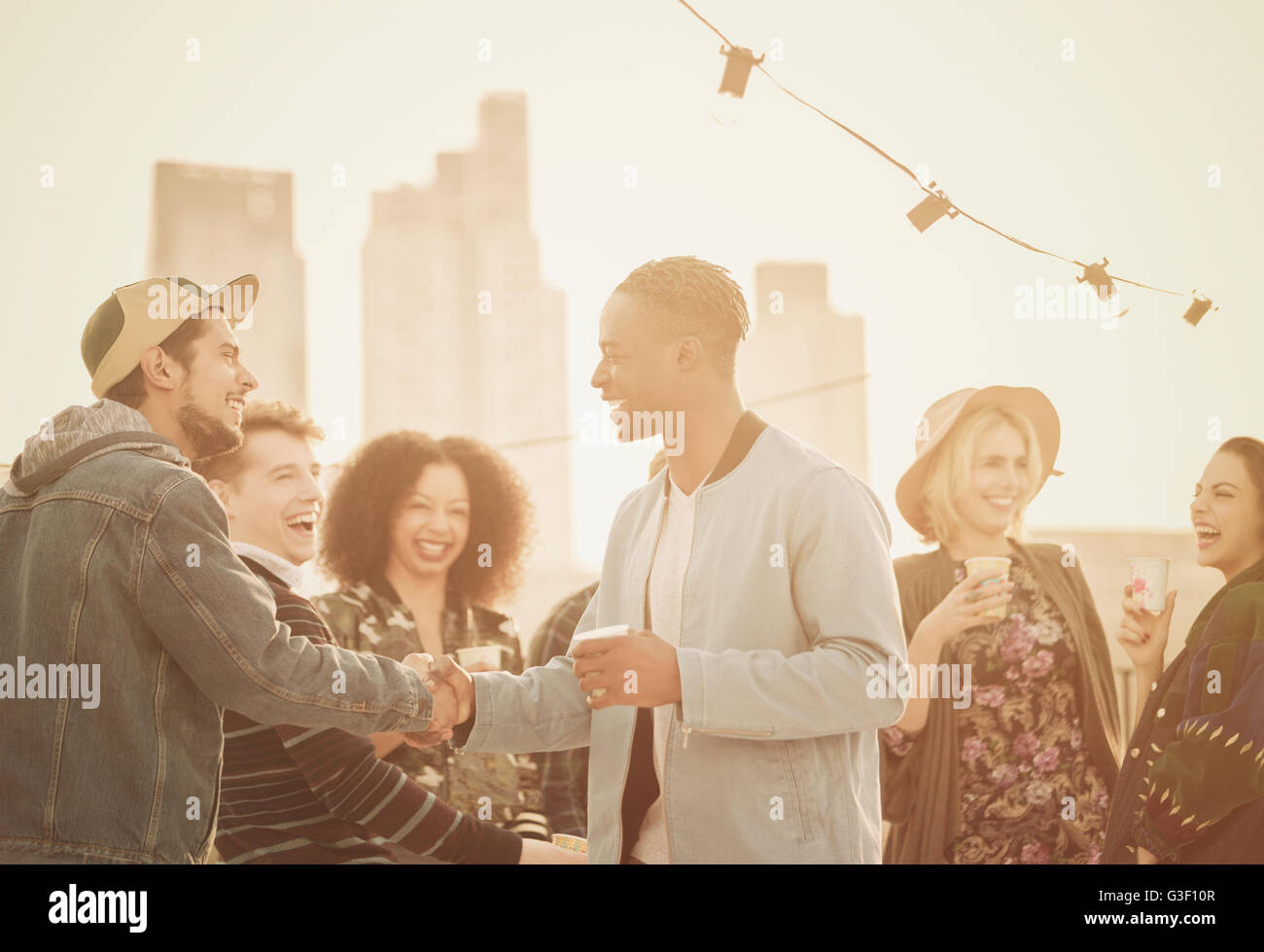 Young adult friends handshaking at rooftop party Stock Photo - Alamy