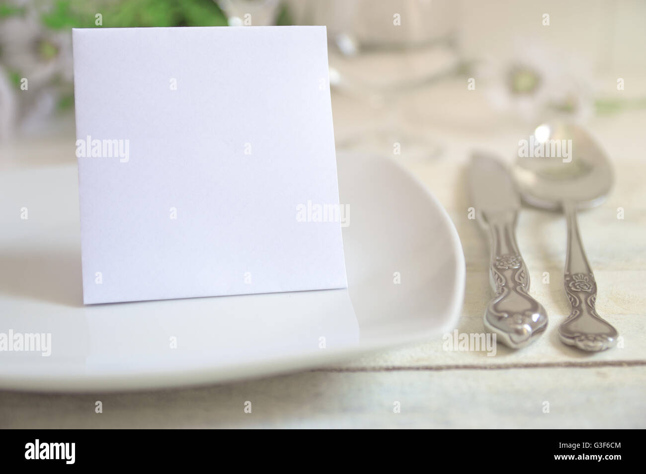 Invitation card on a decorated table with classic cutlery and some ...