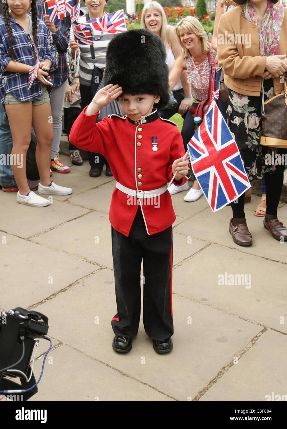 A young boy dressed in a Guardsman outfit surrounded by tourists before ...