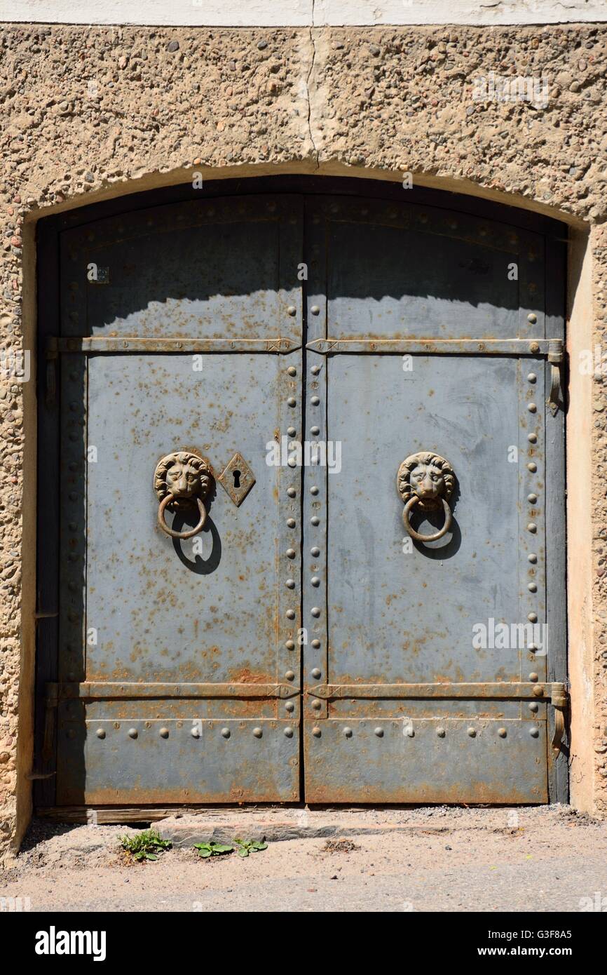 An old heavy iron door with lion motif handles. Some rust can be seen ...