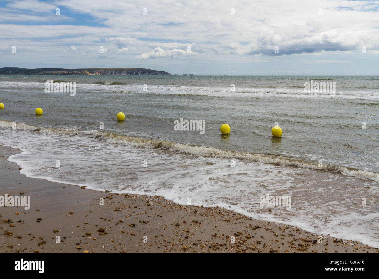 UK pebble beach with line of yellow buoys. Isle of Wight Needles in ...