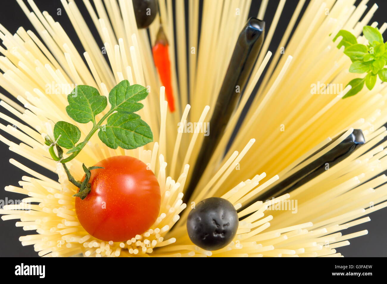 Raw spaghetti with tomato and olives placed in spiral shape ready for ...