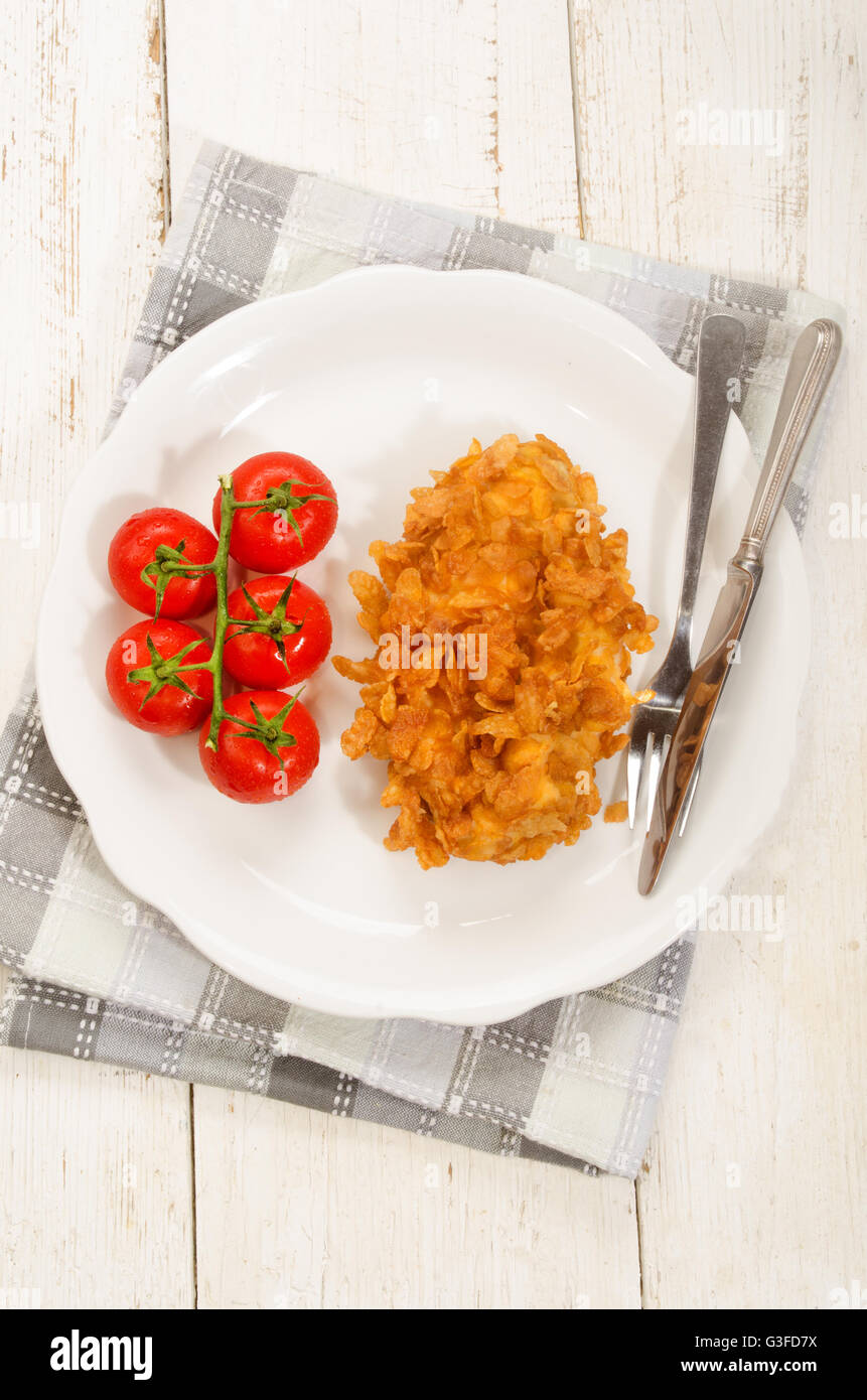 deep fried chicken fillet coated with corn flakes and wet tomato on a ...