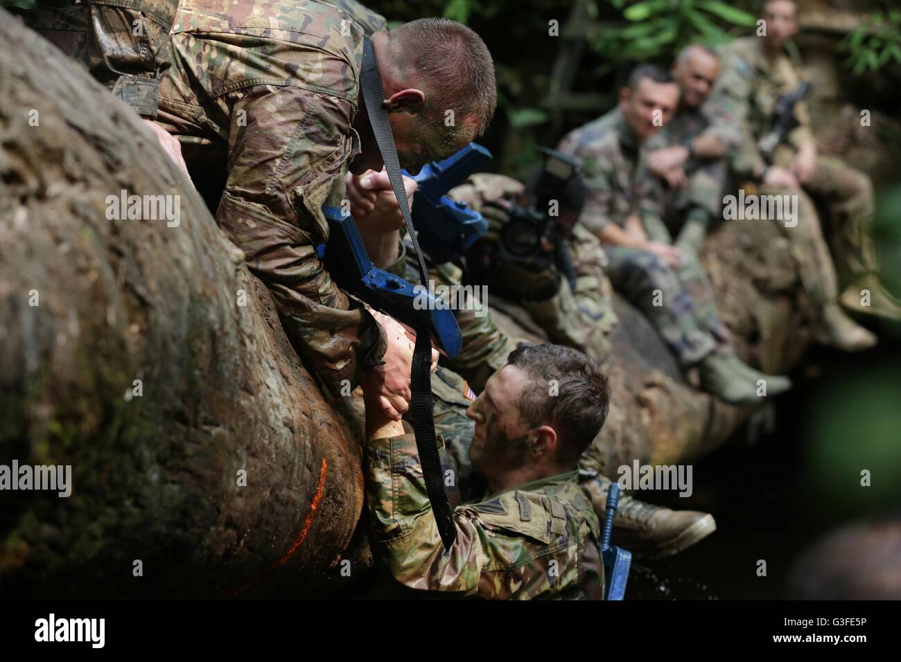 U.S. Army soldiers help each other over a log during the team obstacle ...