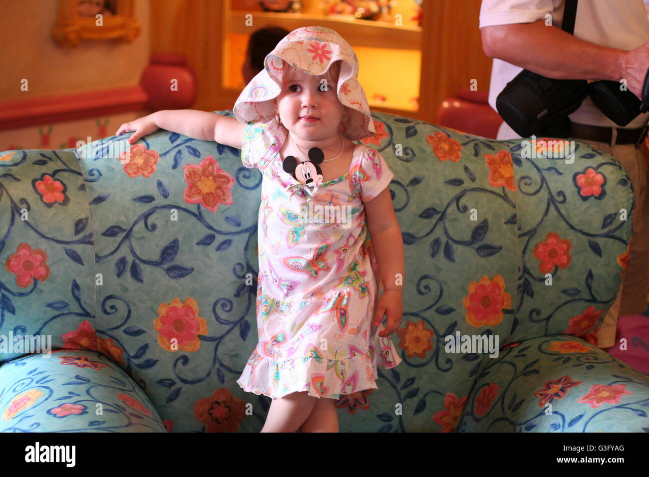 Little girl standing on minnie mouse chair in a sunhat in Minnie Mouses ...