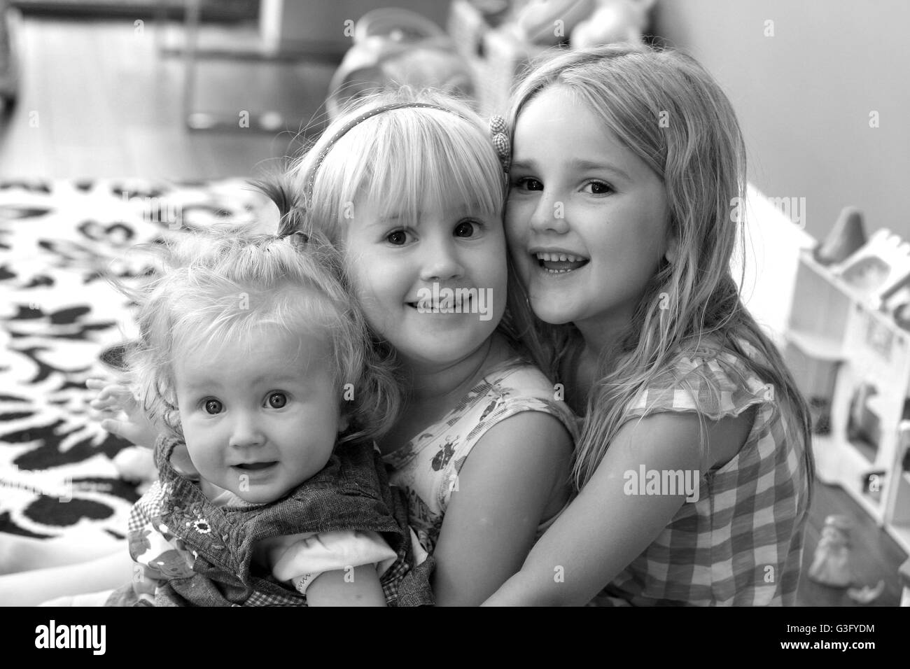 three girls, children sitting closely together cuddled like a train ...