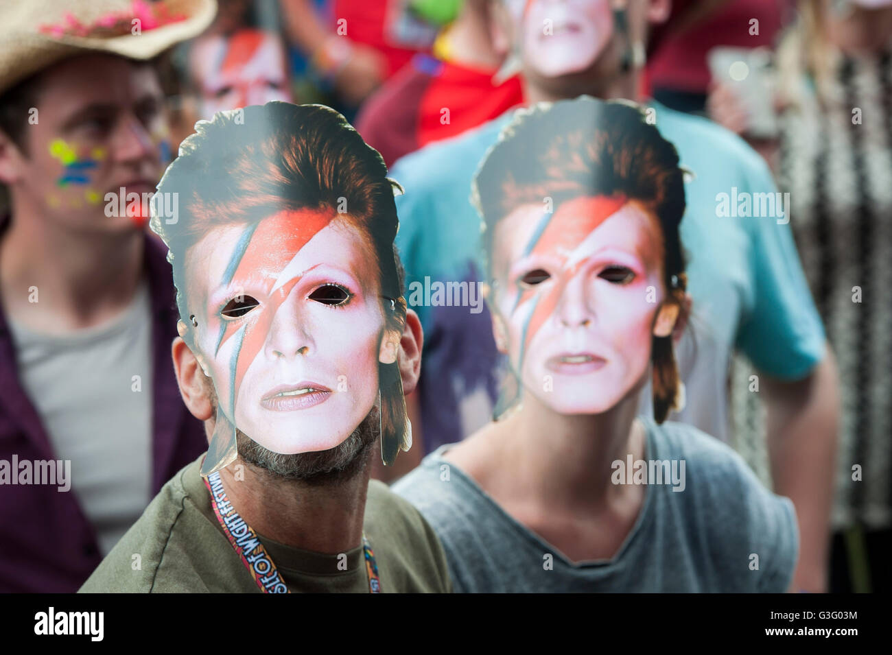 Festival goers wear David Bowie masks during a tribute to David Bowie ...