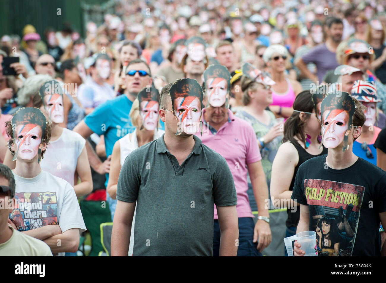 Festival goers wear David Bowie masks during a tribute to David Bowie ...