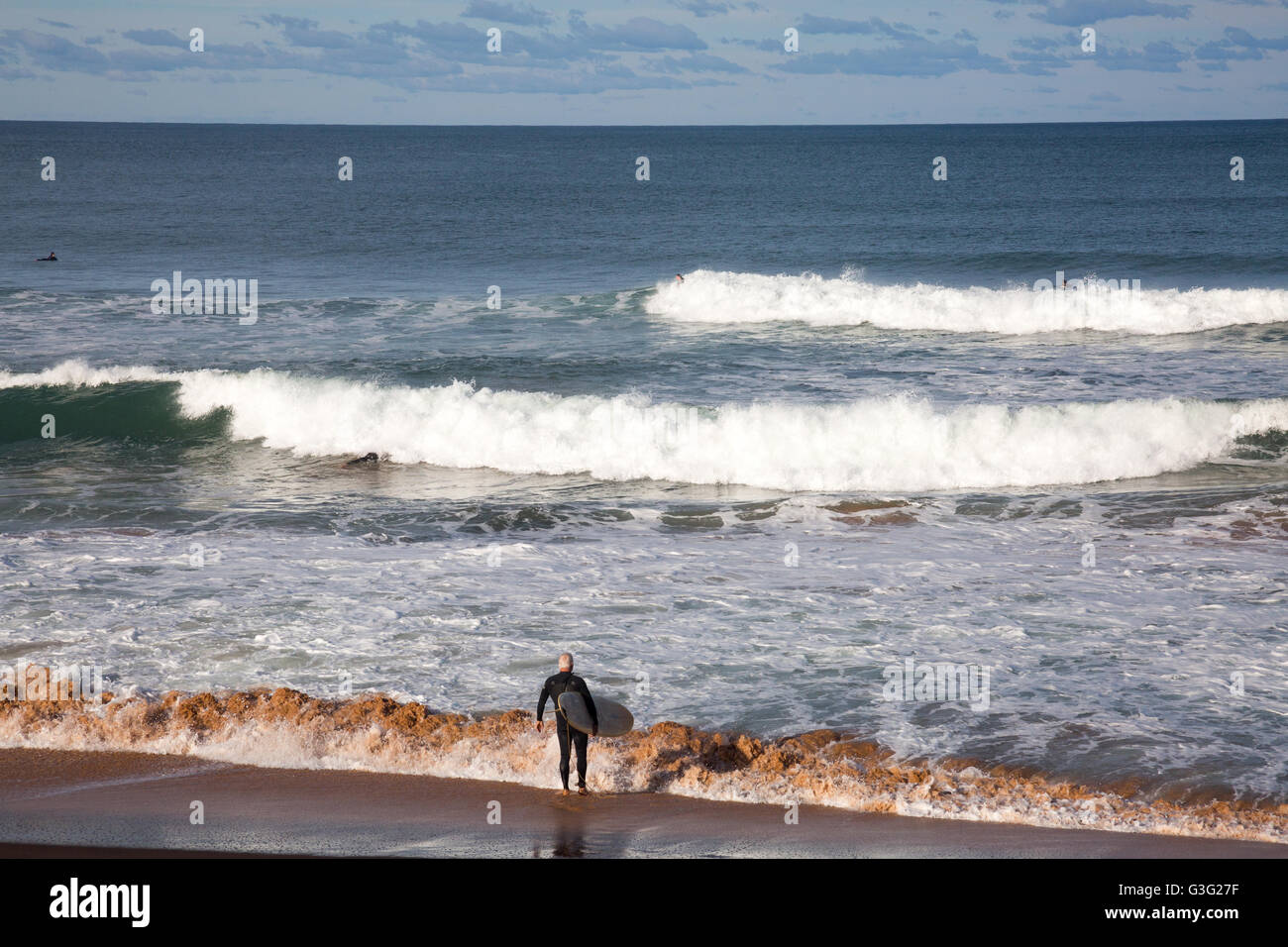 australian man with surfboard enters the ocean at Avalon Beach Sydney ...