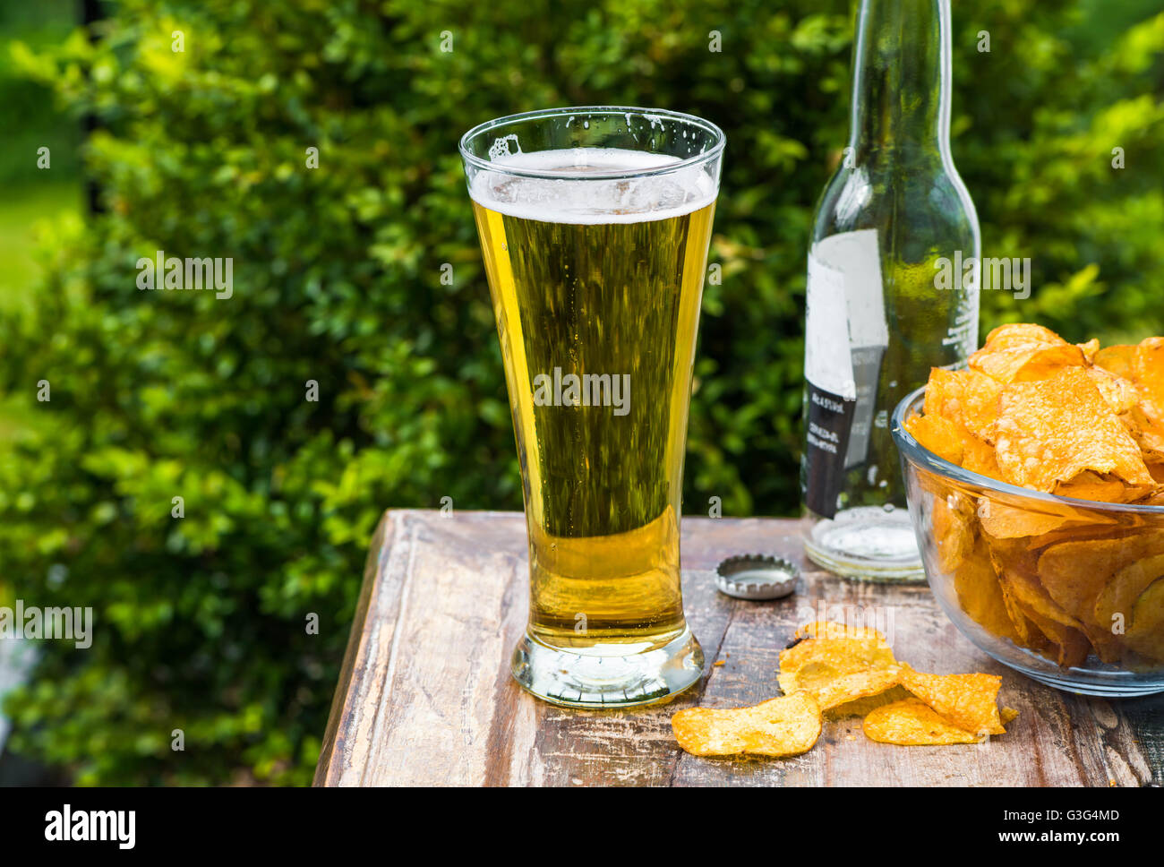 A glass of beer and a bowl of crisps on a table in the garden Stock ...