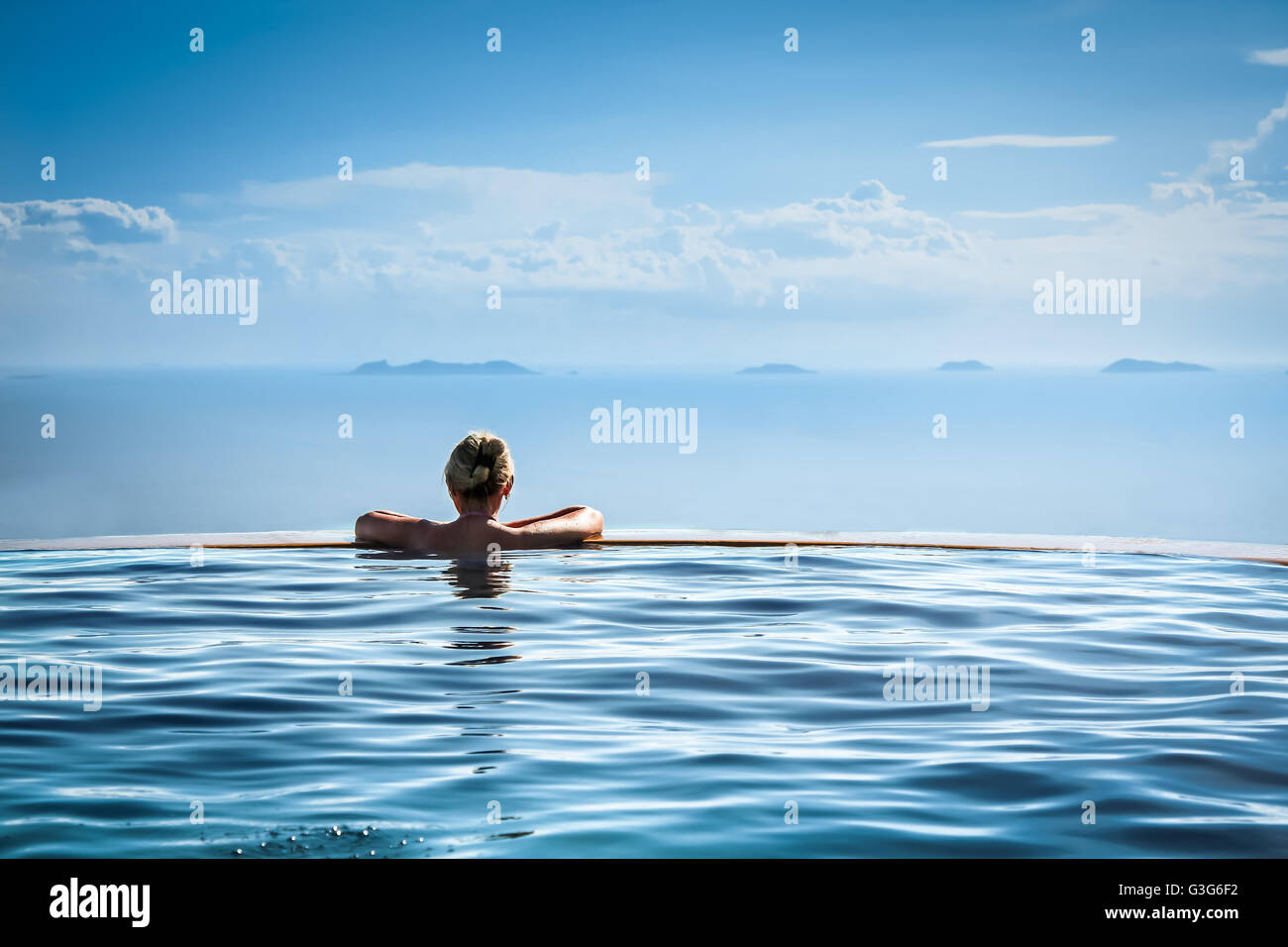 Woman relaxing in infinity swimming pool looking at view Stock Photo ...