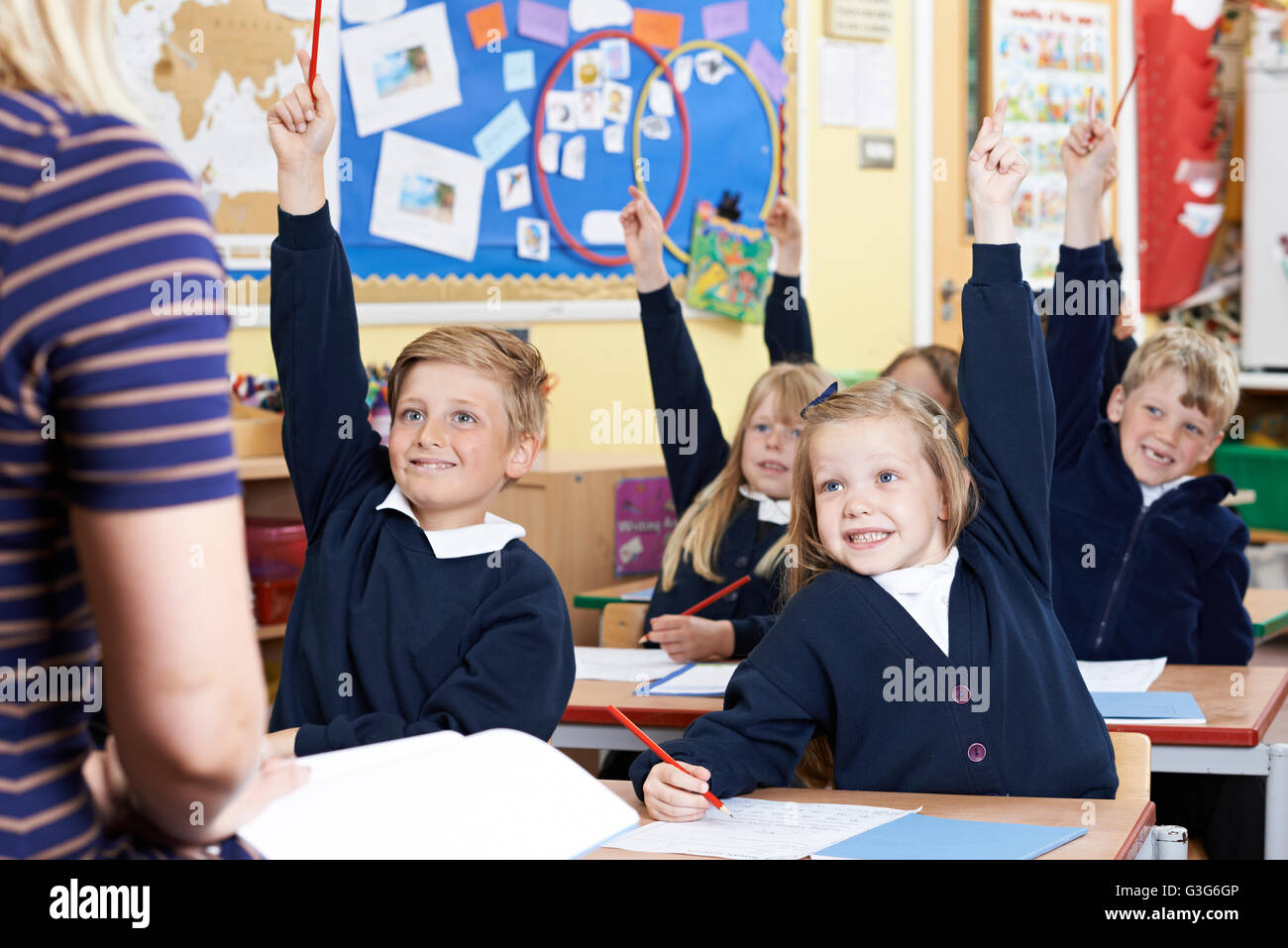 Class Of Elementary School Pupils Answering Question Stock Photo - Alamy