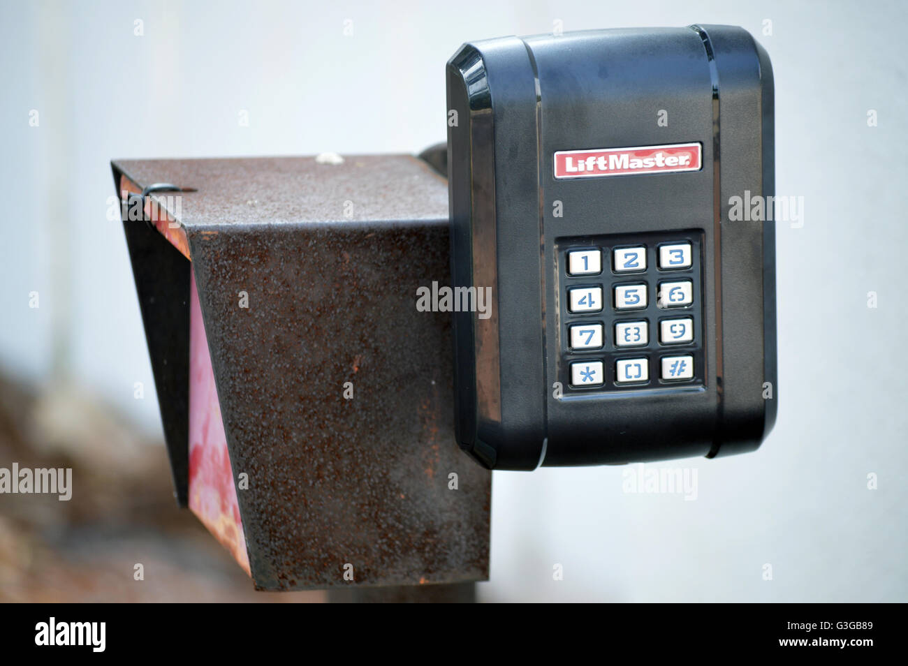 A black plastic LiftMaster Entry keypad mounted on a rusty red and ...