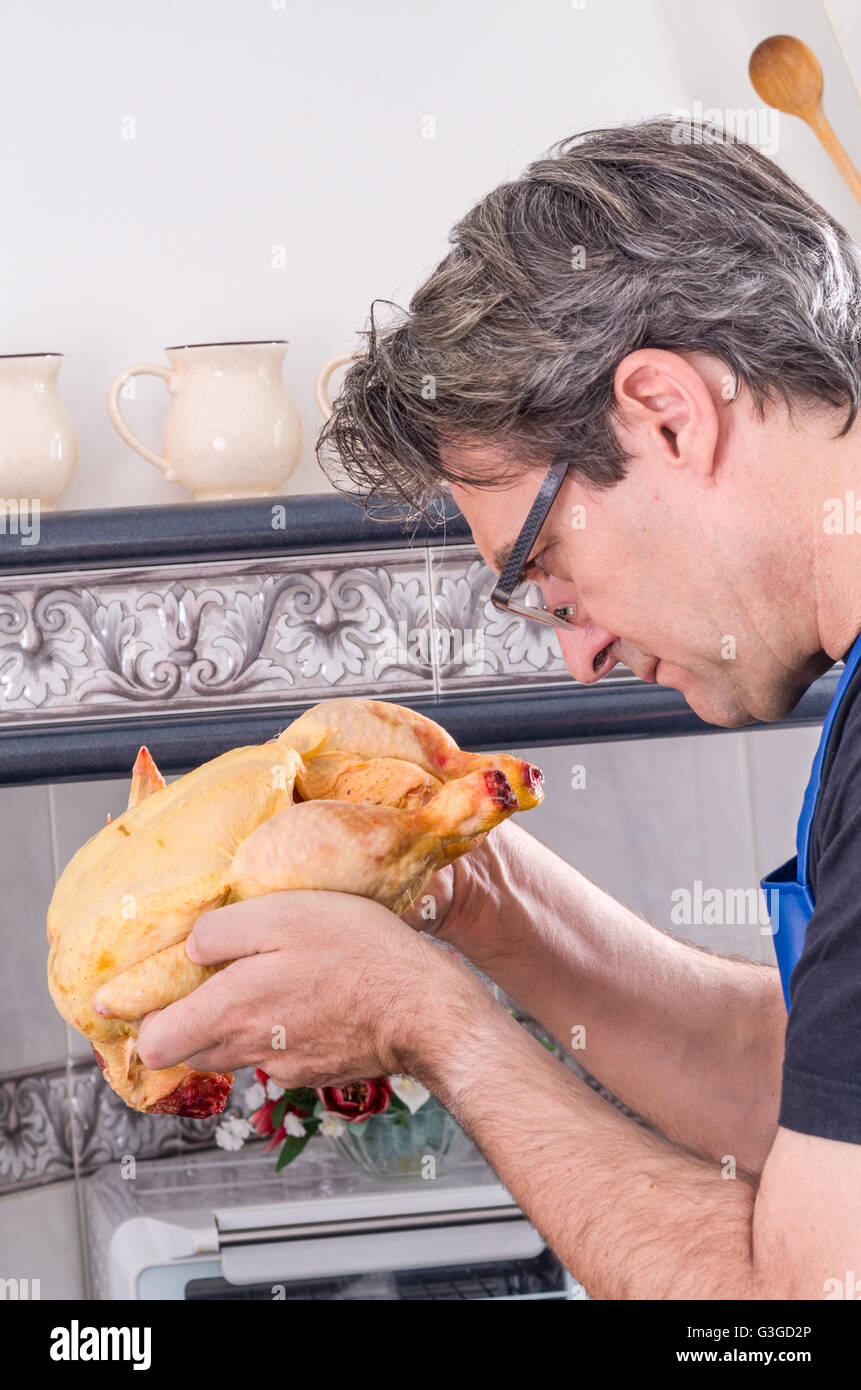 First time a guy faces a raw chicken in the kitchen Stock Photo - Alamy