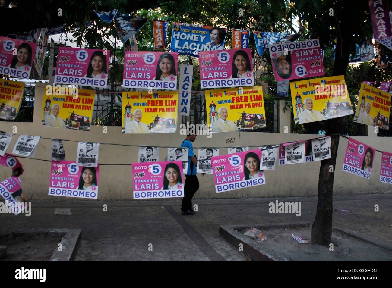 Filipinos walk past campaign banners of candidates for elections as ...