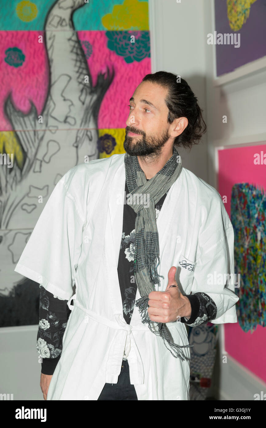Adrien Brody poses in front of his paintings during preview at Art New ...