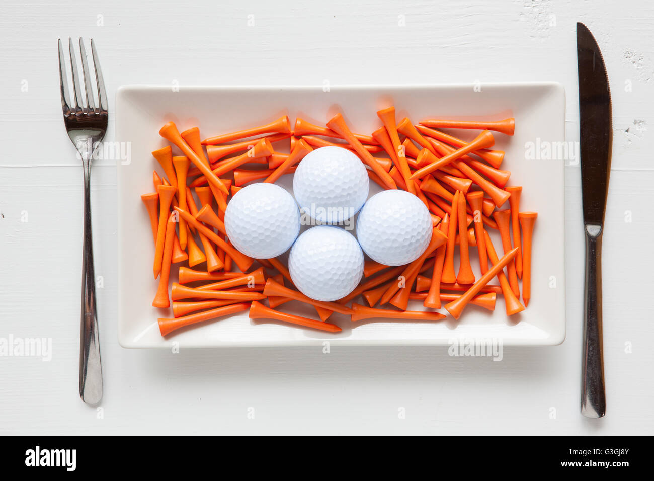 White ceramic dishes with golf balls and wooden tees on over white ...