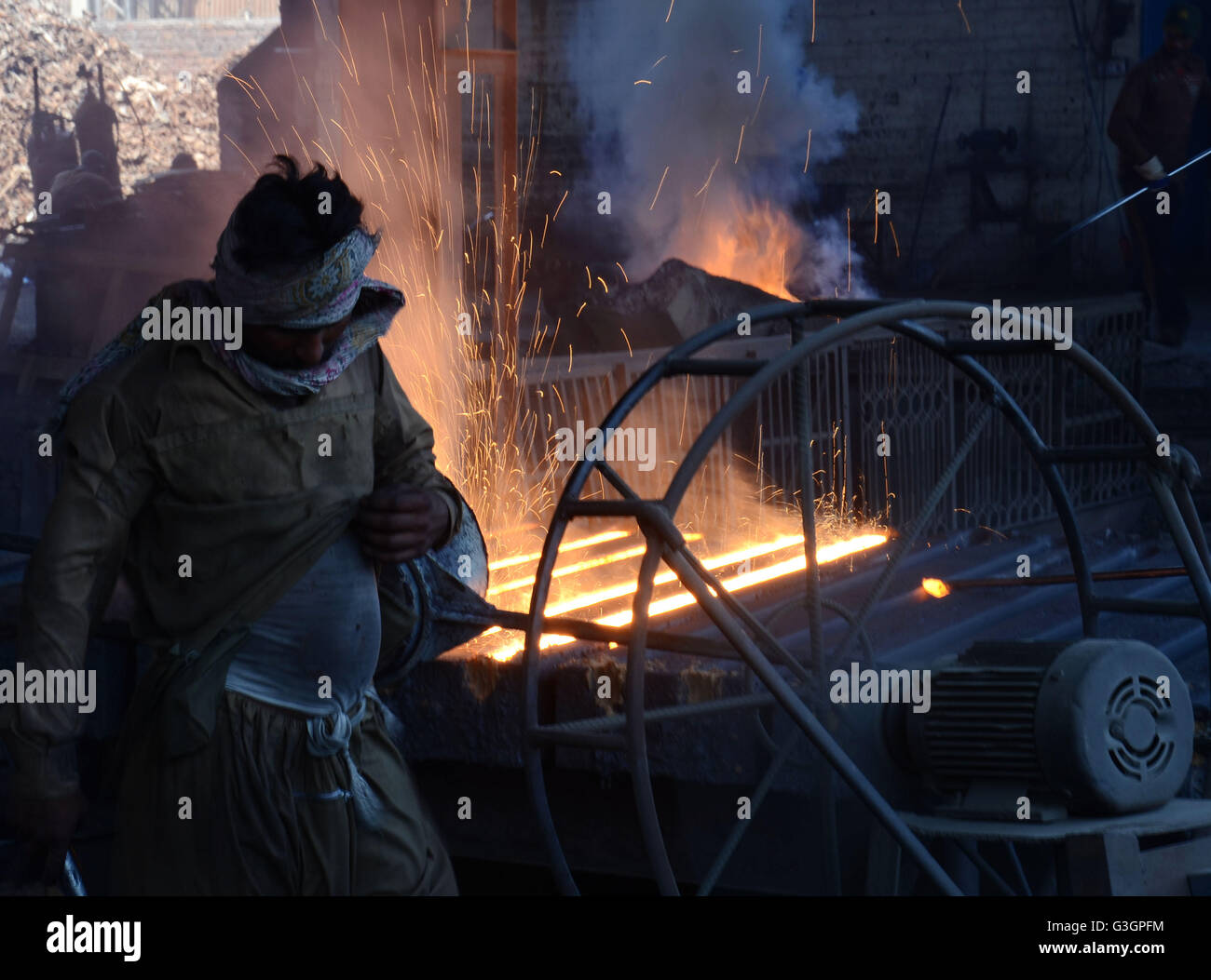 Pakistani blacksmiths work at an iron molding factory in an industrial ...