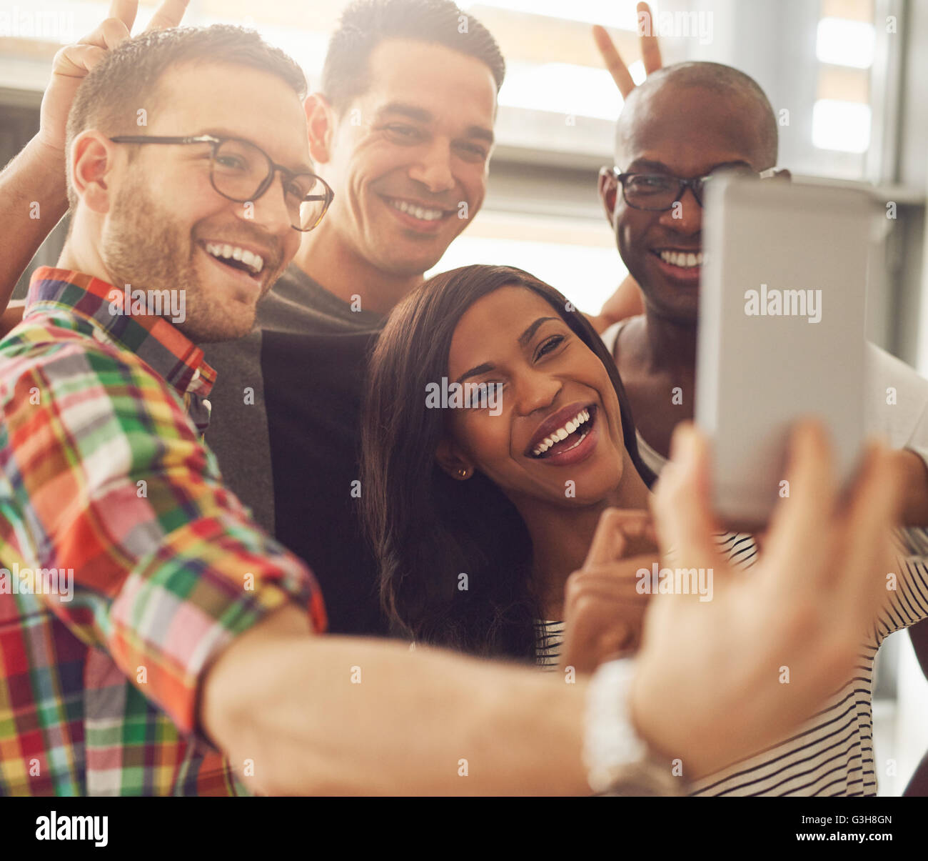Group of four diverse cheerful co-workers taking self portrait and ...