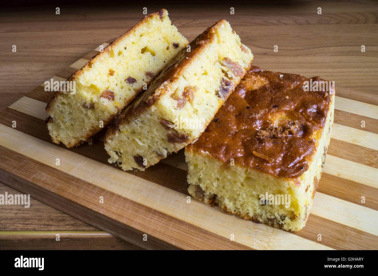 Sweet fruit cake with raisins on striped kitchen board on wooden table ...