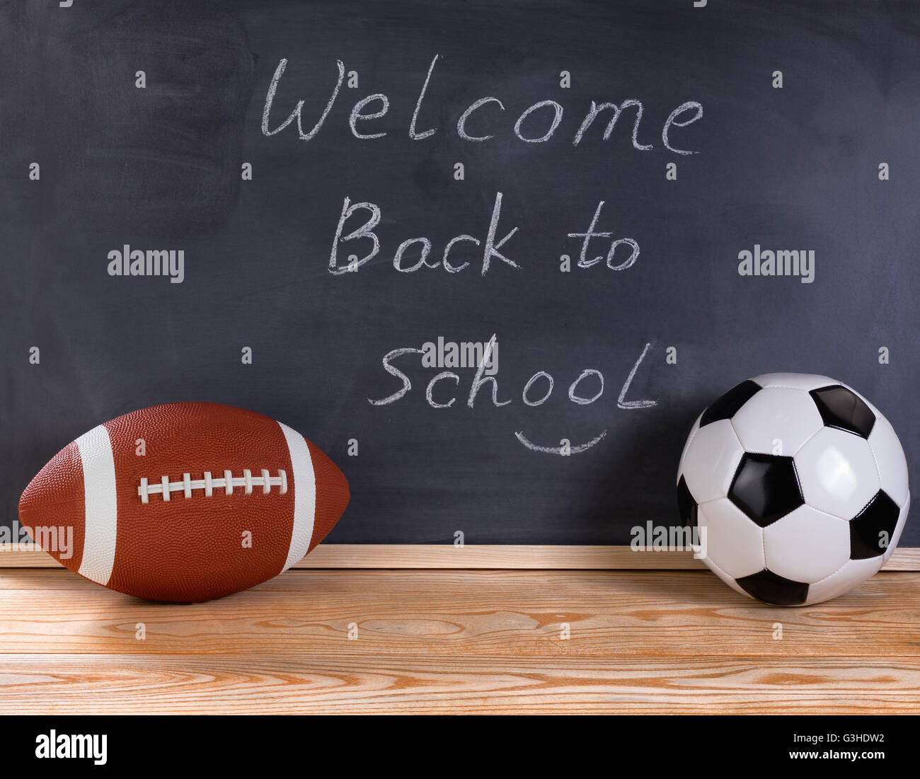 Football and soccer ball on desktop. Erased black chalkboard in ...