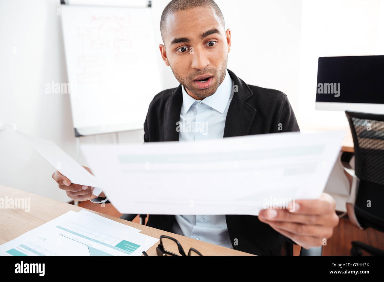 Smart shocked businessman looking at paper and holding eyeglasses Stock ...