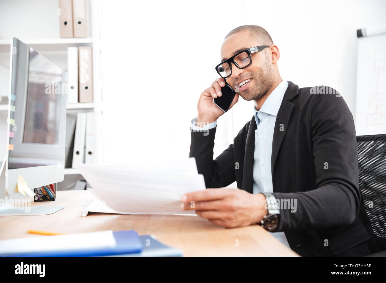 Office worker calling on the phone and reading business document in the ...