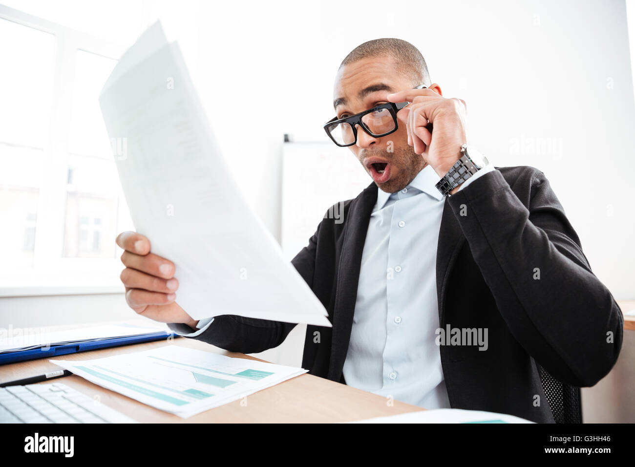 Smart shocked businessman looking at paper and holding eyeglasses Stock ...