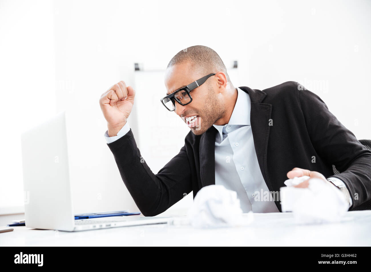 Angry nervous businessman working at office desk overloaded with ...