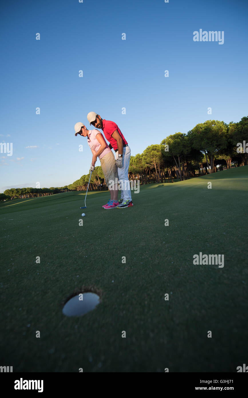 male golf instructor teaching female golf player, personal trainer ...