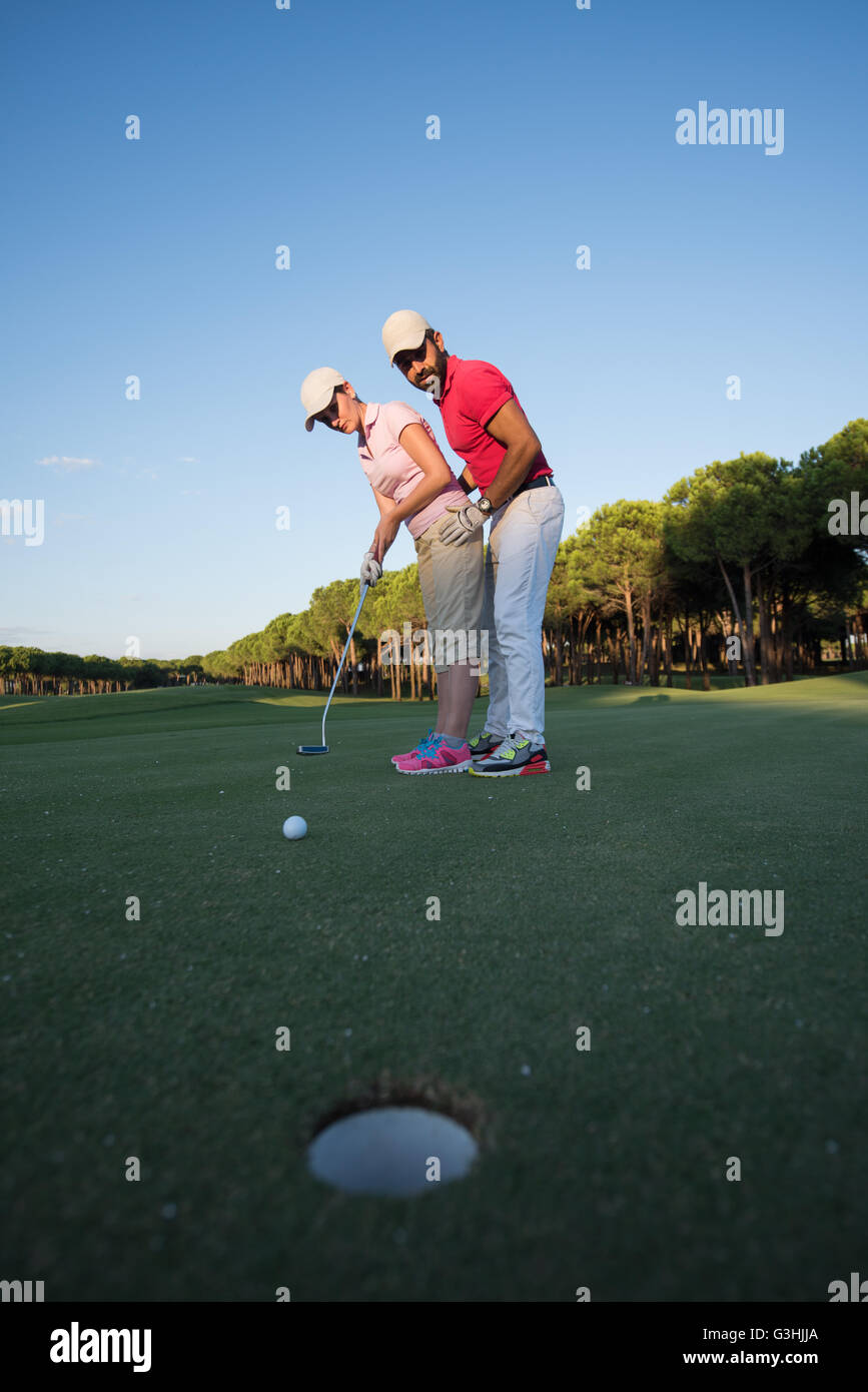 male golf instructor teaching female golf player, personal trainer ...