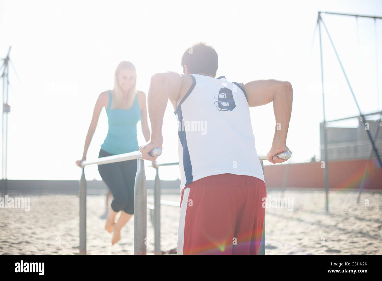 Couple exercising on beach, using gymnastics parallel bars Stock Photo ...