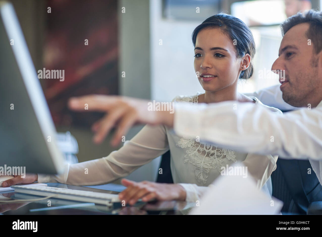 Male designer pointing to desktop computer at meeting in design office ...