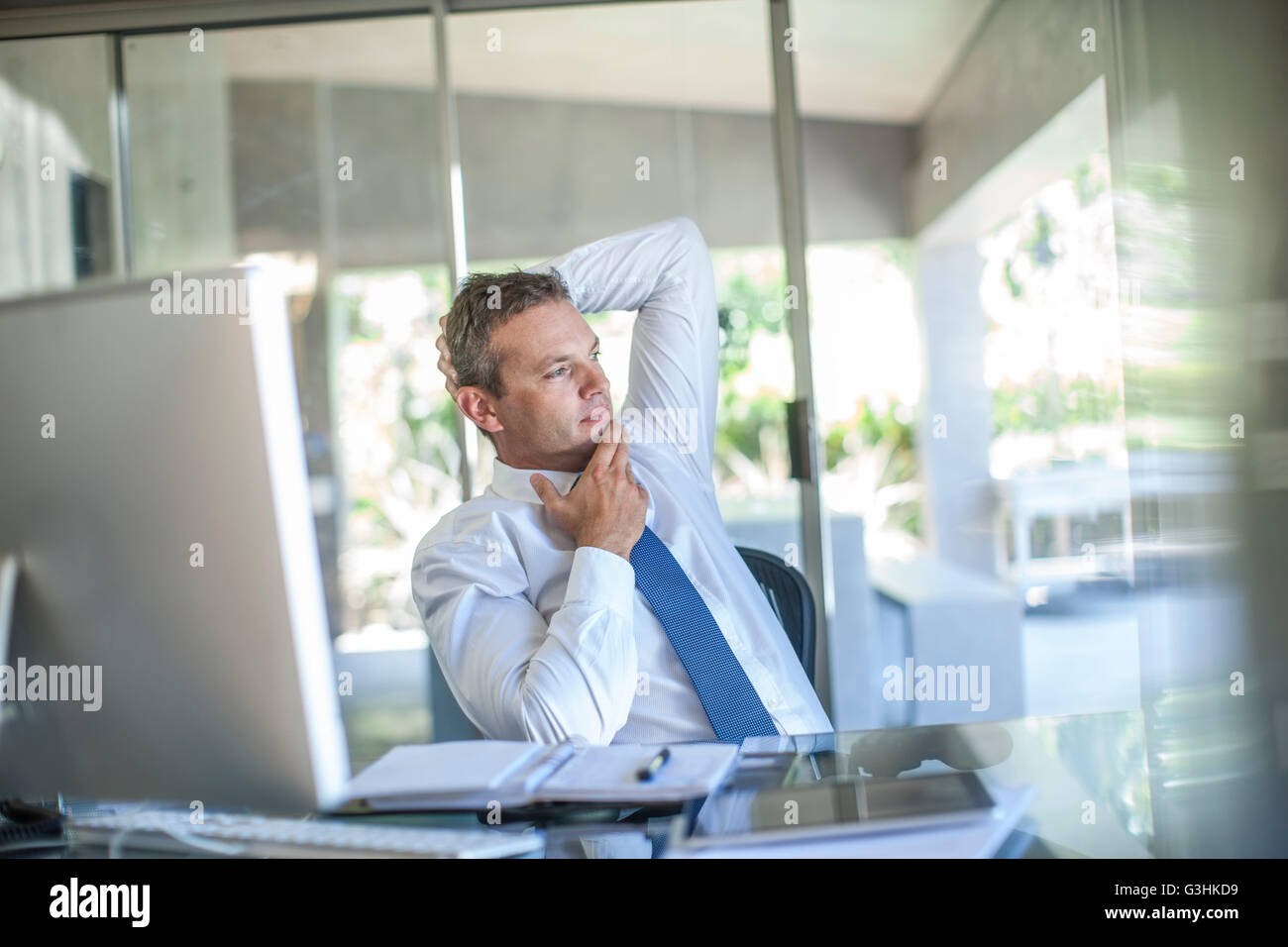 Businessman gazing through window from office desk Stock Photo - Alamy