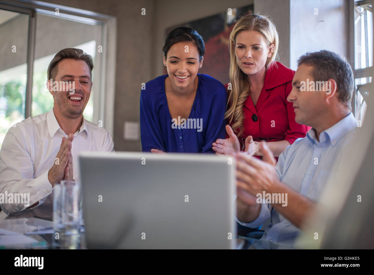 Happy design team meeting around laptop at boardroom table Stock Photo ...