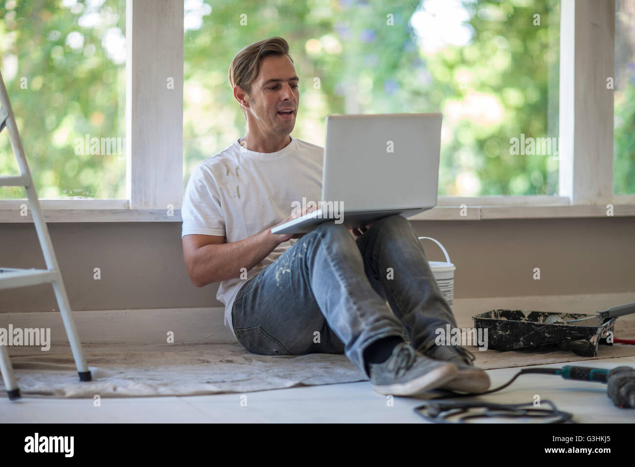 Builder using laptop on floor Stock Photo - Alamy