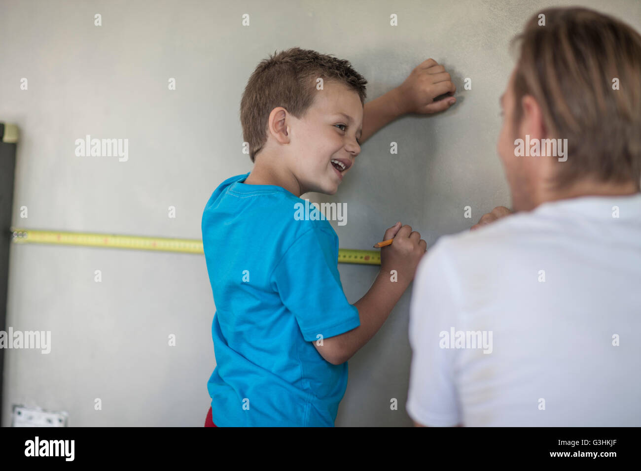 Builder and son measuring wall Stock Photo - Alamy