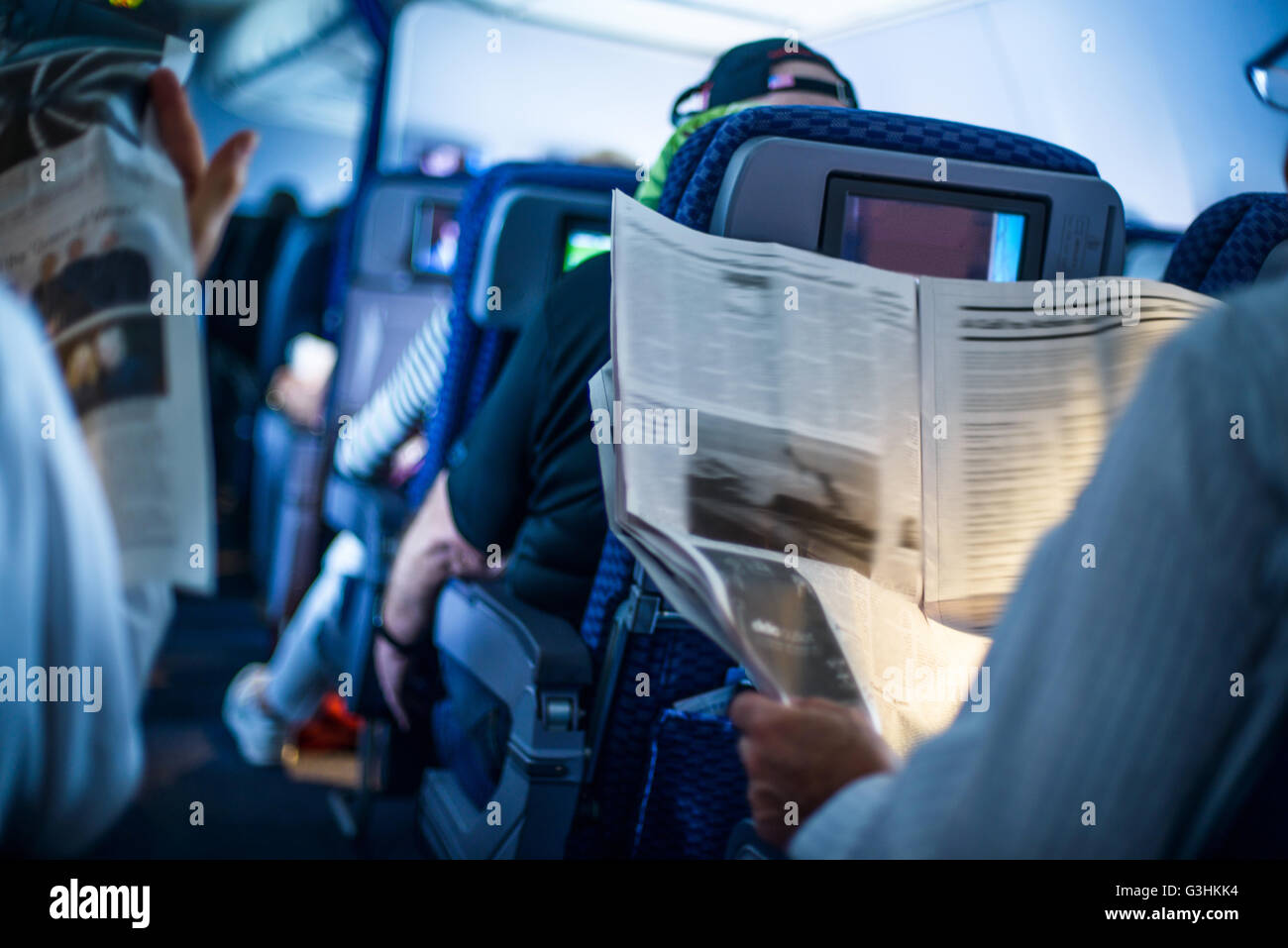 Passengers reading newspapers on board flight Stock Photo - Alamy