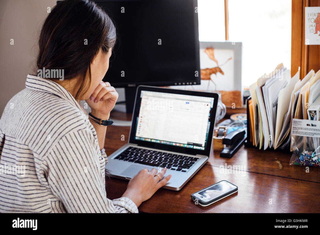 Woman at desk with laptop and stapler hi-res stock photography and ...